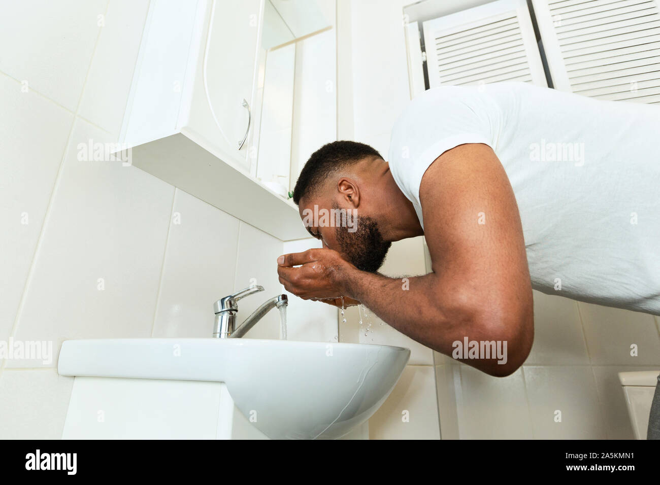 African man washing his face in bathroom Stock Photo - Alamy