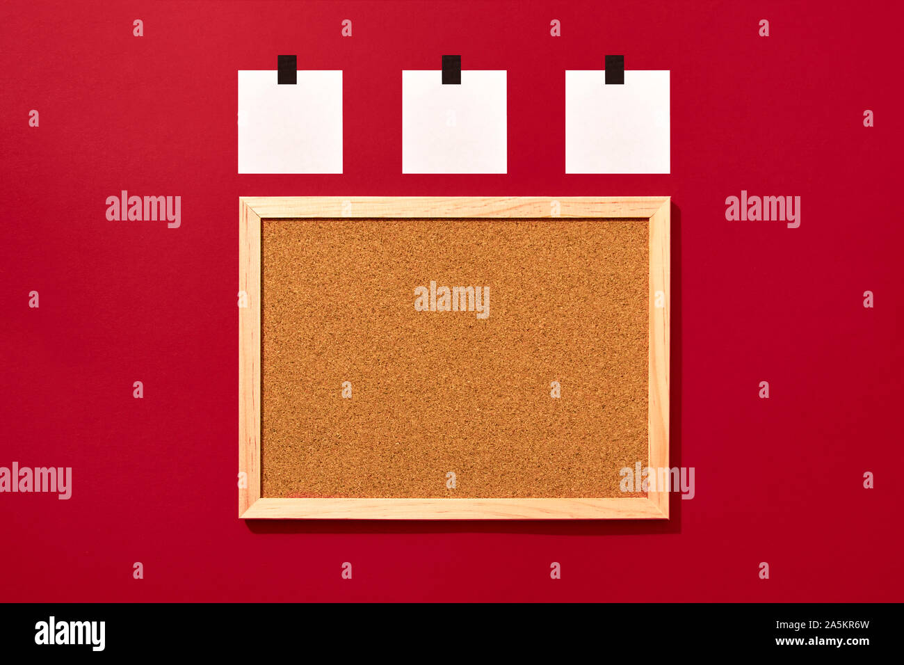 Empty cork board with wooden frame and three blank notes sticked with ...