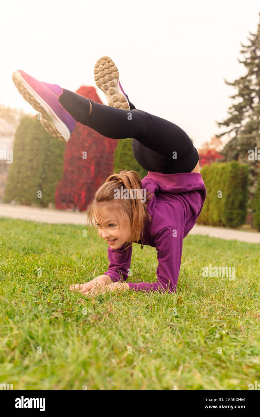 Outdoors leisure. Little gymnast backbend exercising arch variation in ...