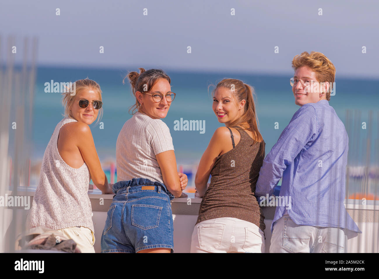 People looking towards the camera smilingly while standing on sunny day ...