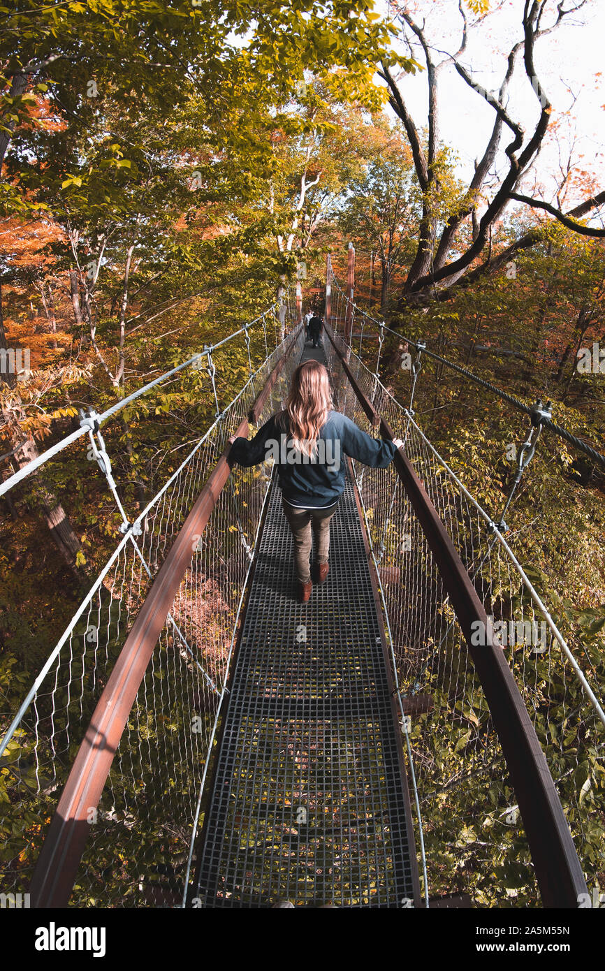 Girl walking across a bridge in the fall trees Stock Photo - Alamy
