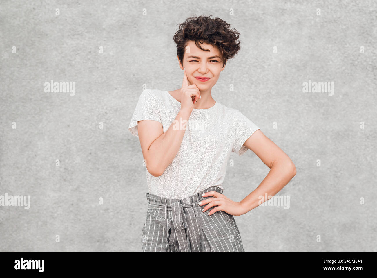 Charming young woman with creative hairstyle is posing with intrigued ...