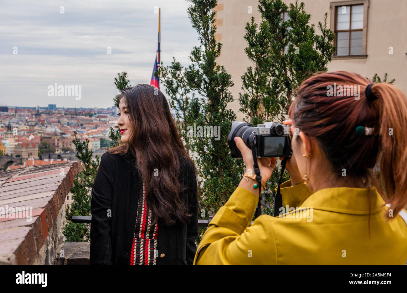 Woman taking side view photograph of friend, cityscape in background ...