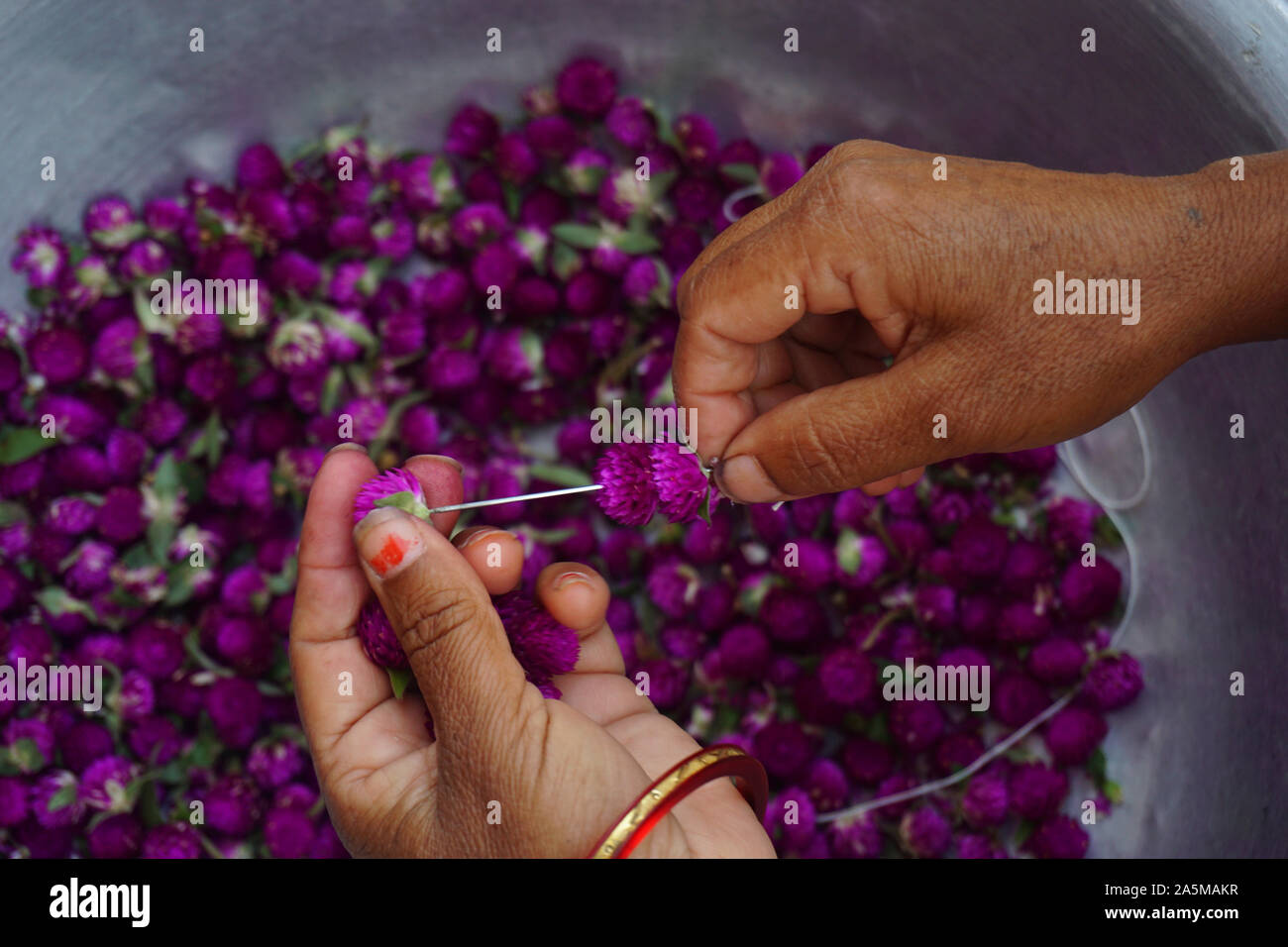 Bhaktapur, Nepal. 21st Oct, 2019. A woman makes garland from the globe ...