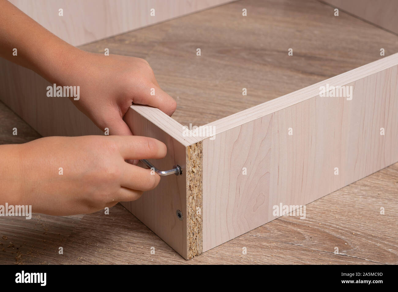 Hands Of A Craftsman Assembling Wood Chipboard Furniture Tightening