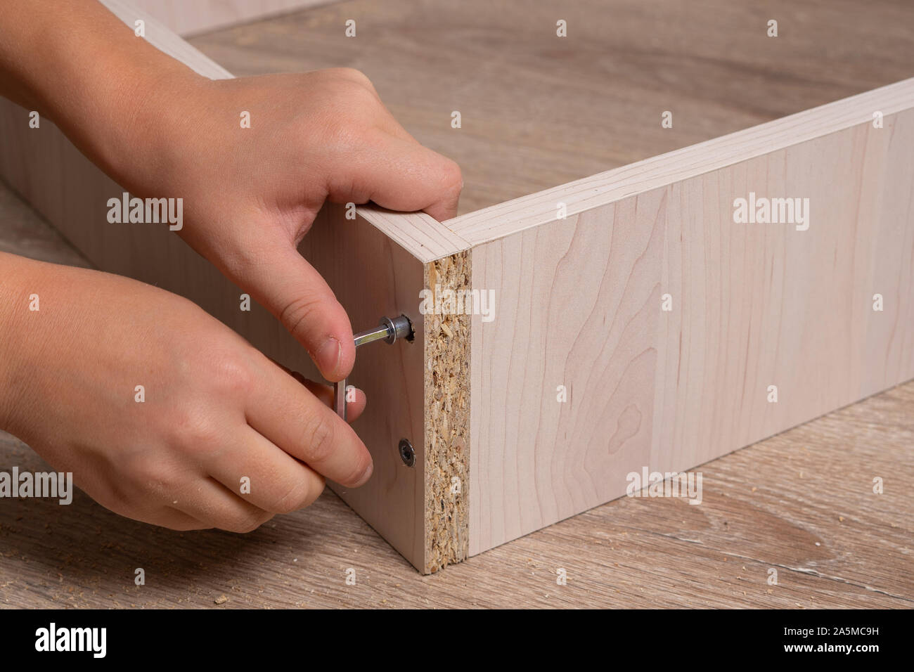Hands Of A Craftsman Assembling Wood Chipboard Furniture Tightening