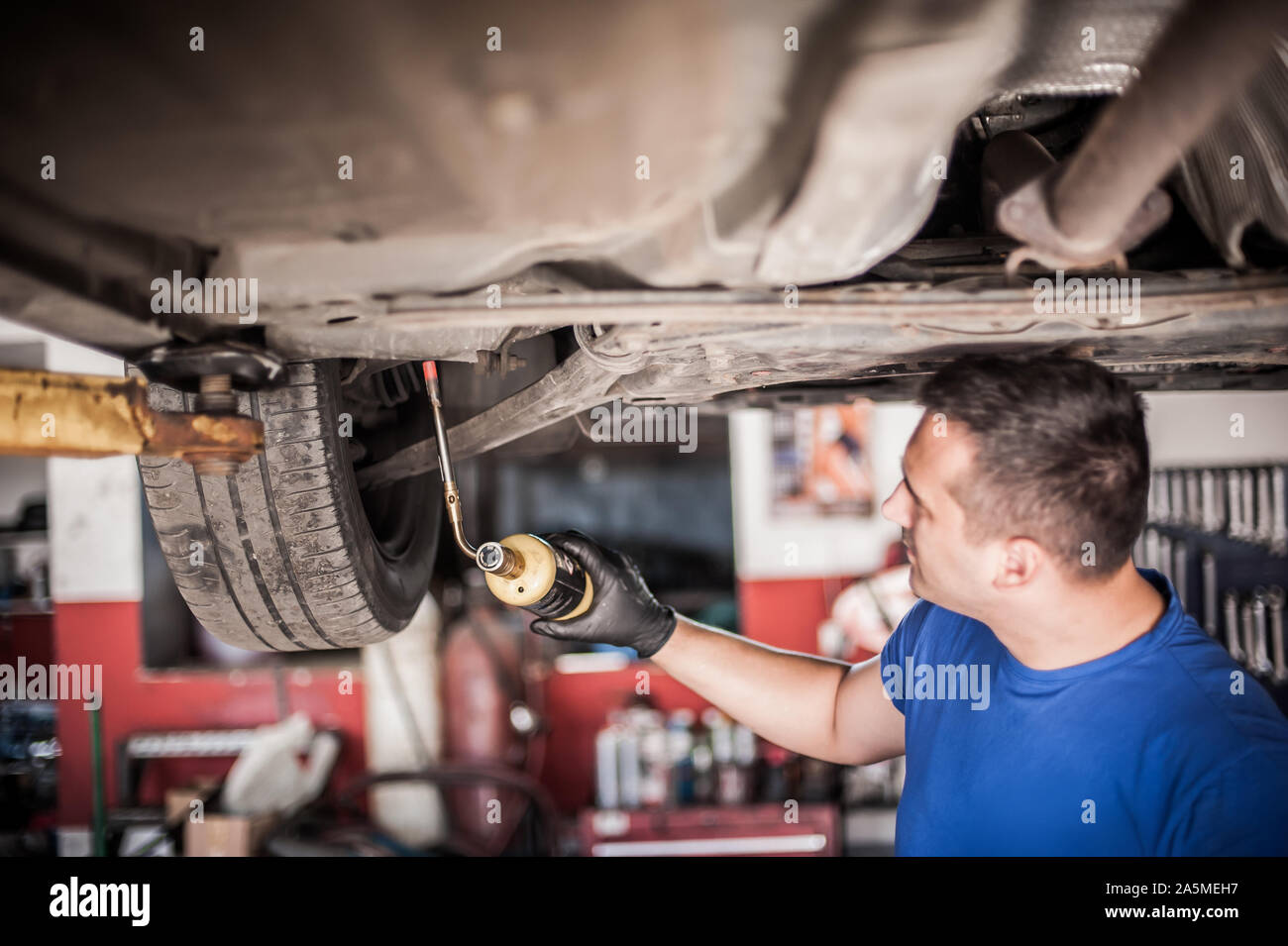 Car master mechanic repairer heating the screws with butane gas blow ...