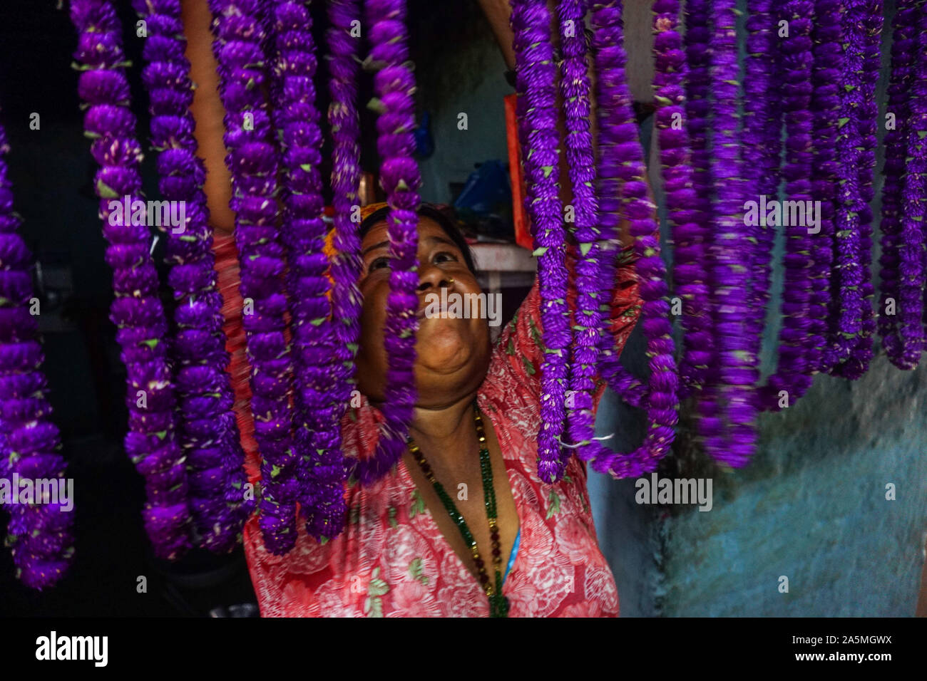 A woman arranges garland made of globe amaranth flower for the upcoming ...