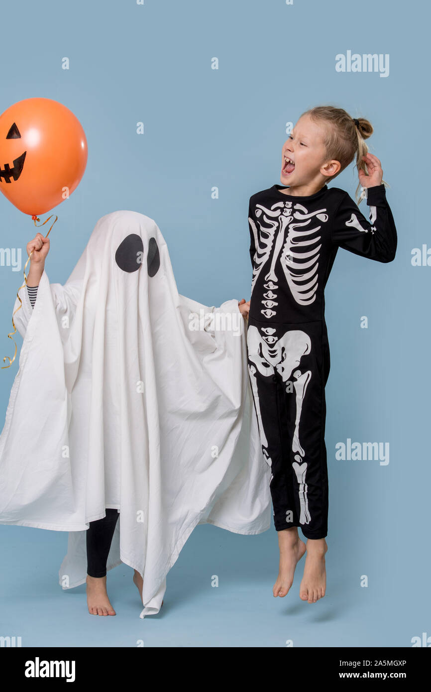 Cute little kids in a ghost and skeleton costumes at Halloween have fun ...