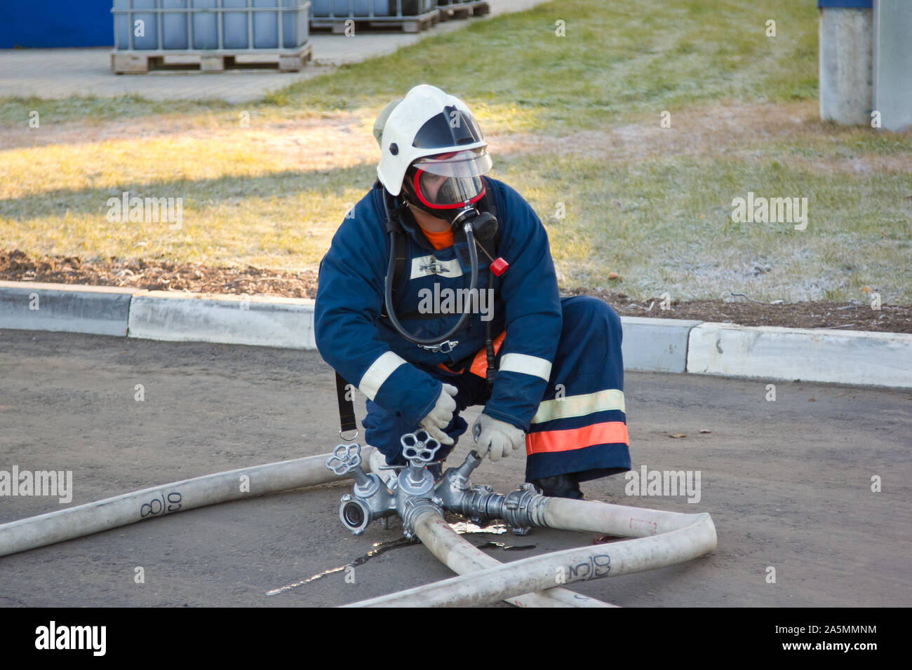Fireman opens valves on firehose for extinguishing fire Stock Photo - Alamy