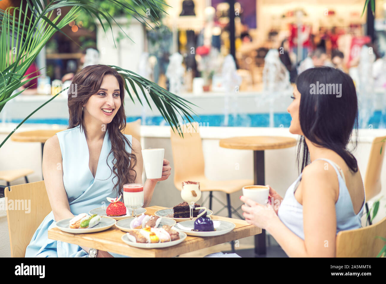 Two beautiful young women are having coffee and desserts together on ...