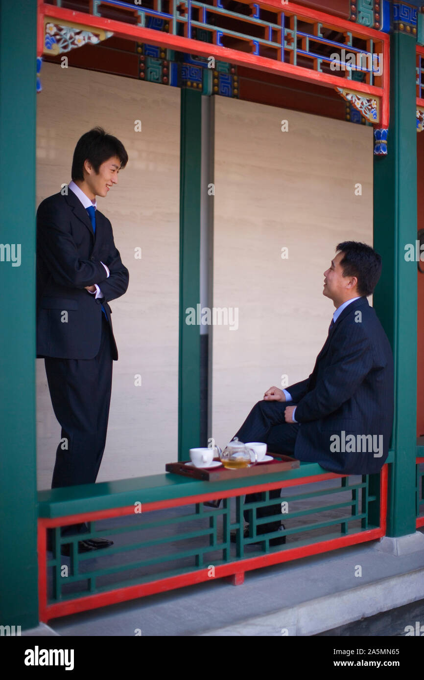 Young adult businessman having tea with a mid-adult male colleague ...