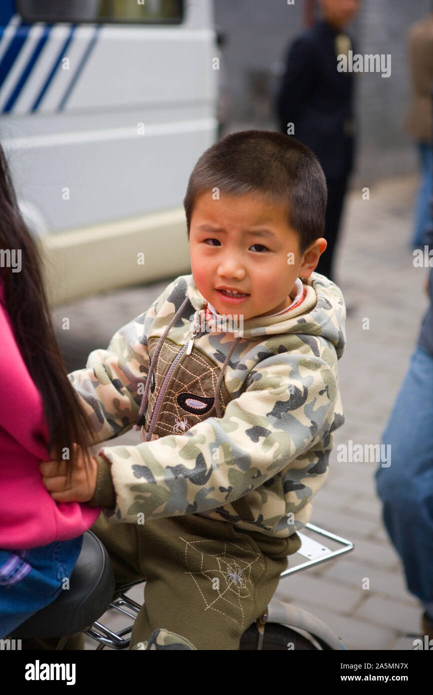 Preschool age Chinese boy sitting on the back of a bike Stock Photo - Alamy