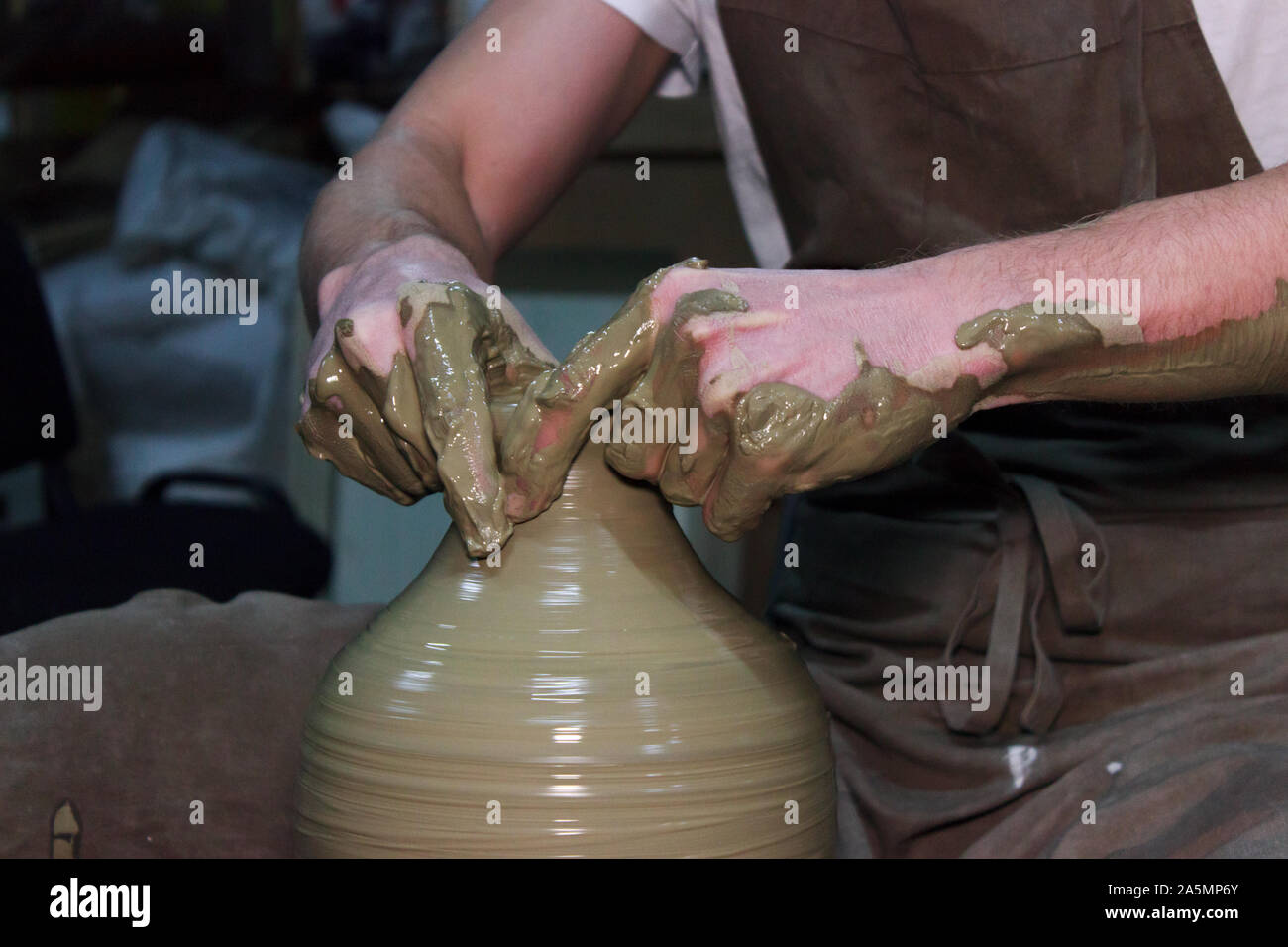 experienced potter makes a large vase on a potter's wheel. twisting a ...