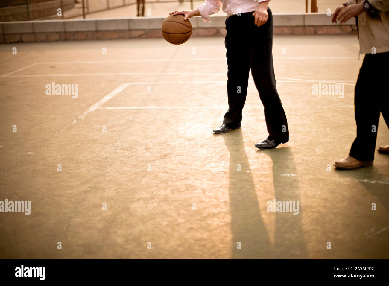 Basketball being bounced on a court outside Stock Photo - Alamy