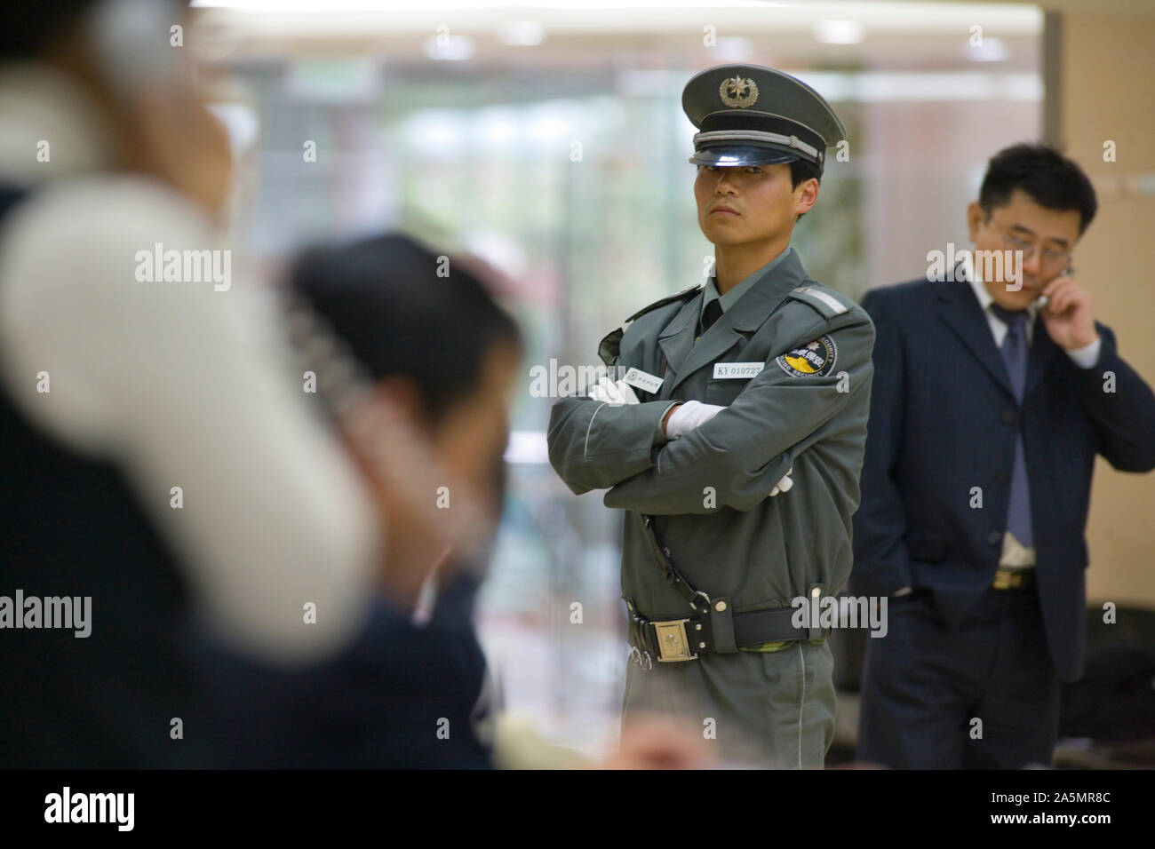 Uniformed security guard watching over customers with his arms crossed ...