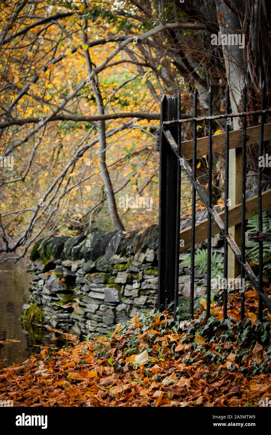 An overgrown gate by the river flowing through the village of Luss ...