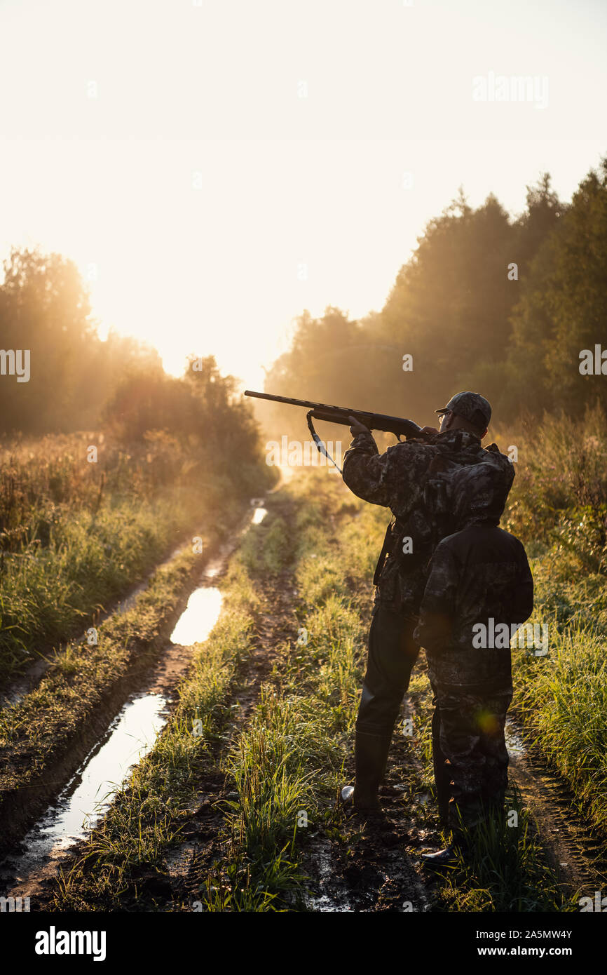 Rifle Hunter and His Son Silhouetted in Beautiful Sunset. Huntsman with ...