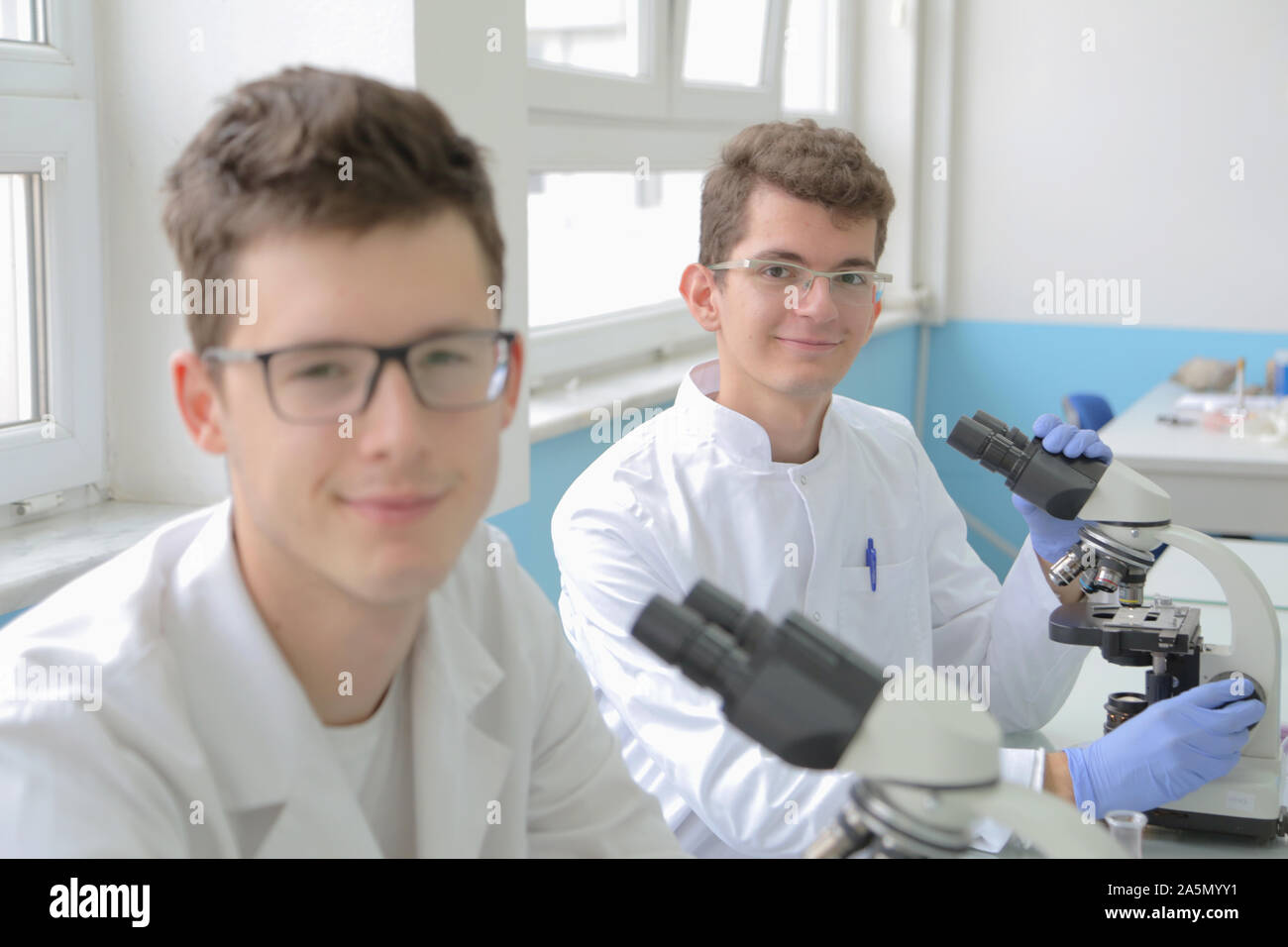 Two Young male scientists looking through a microscope in a laboratory ...