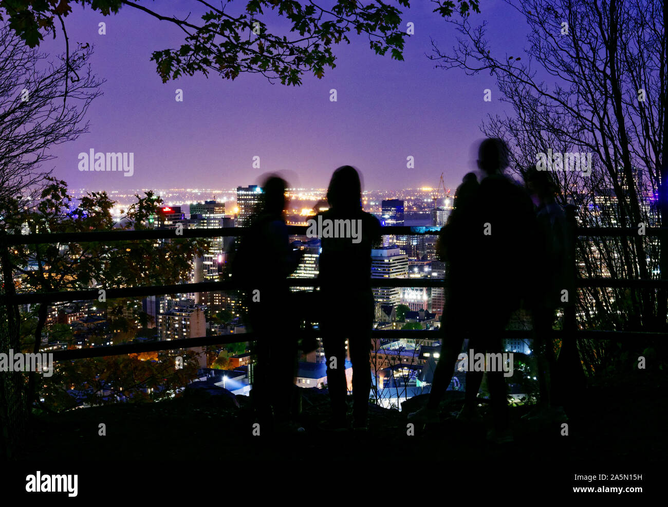 People looking out over Montreal city centre at dusk from a viewpoint ...