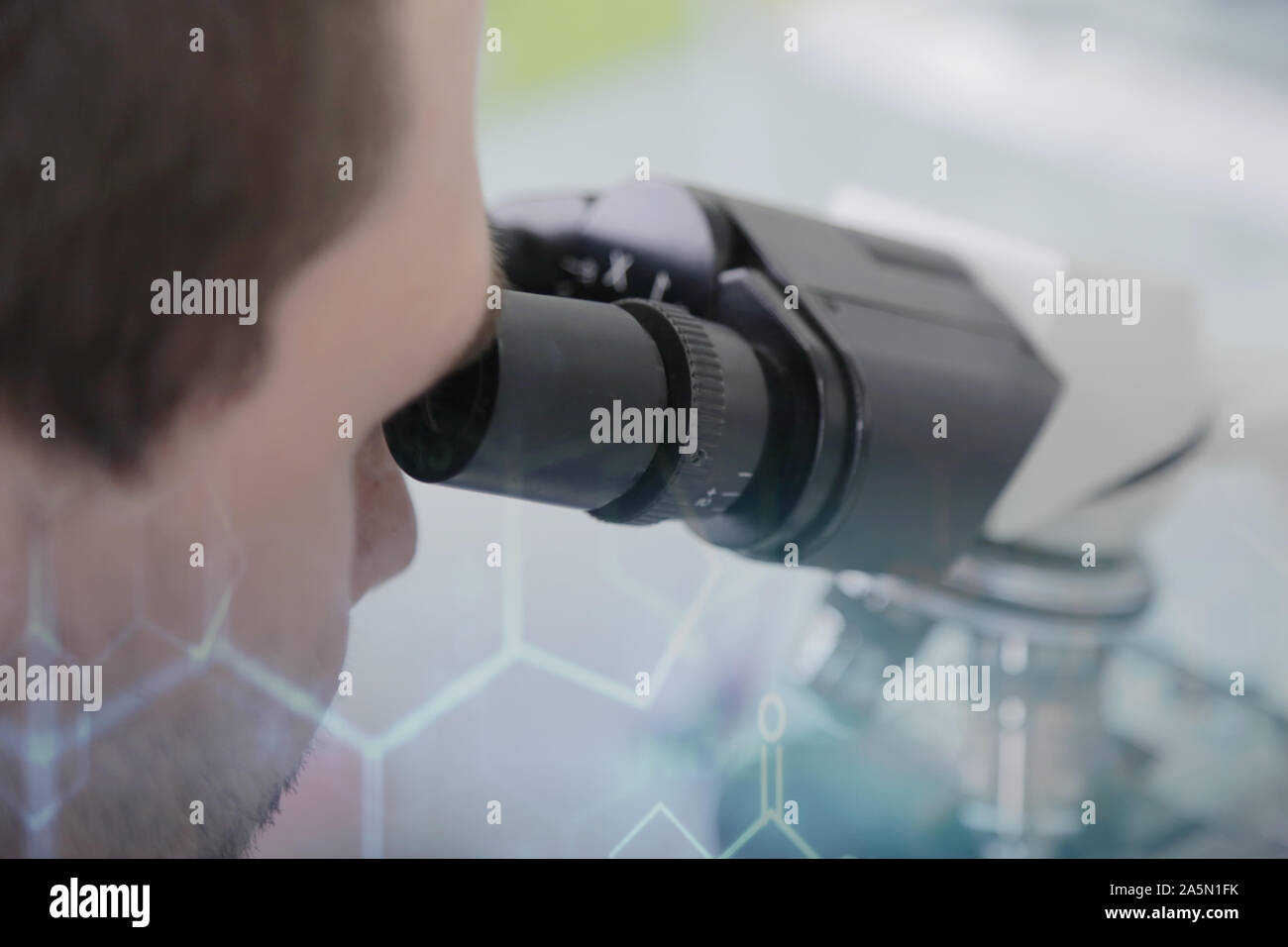 Young male male scientist looking through a microscope in a laboratory ...
