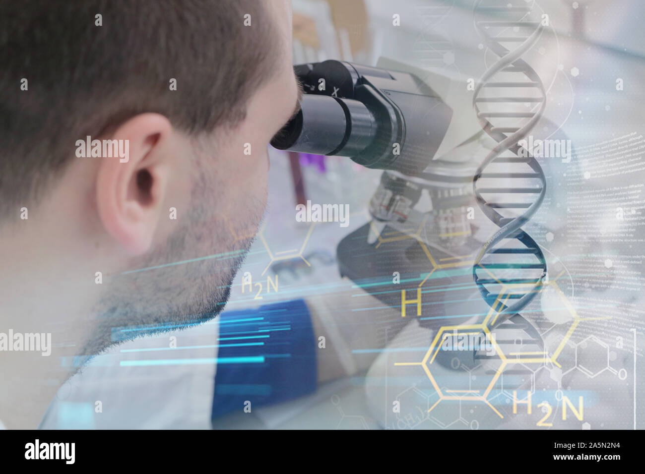 Young male male scientist looking through a microscope in a laboratory ...