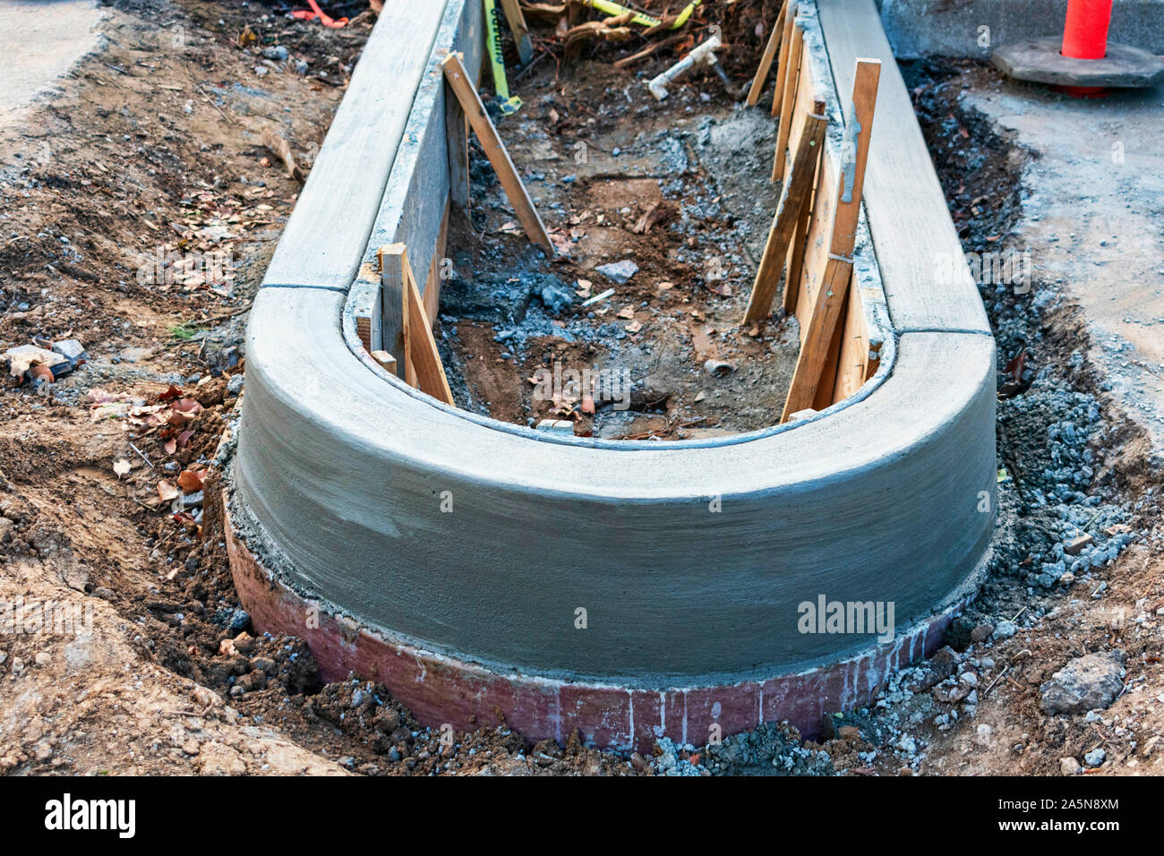 Concrete curb installation. Excavated area. Wood board secured upright ...