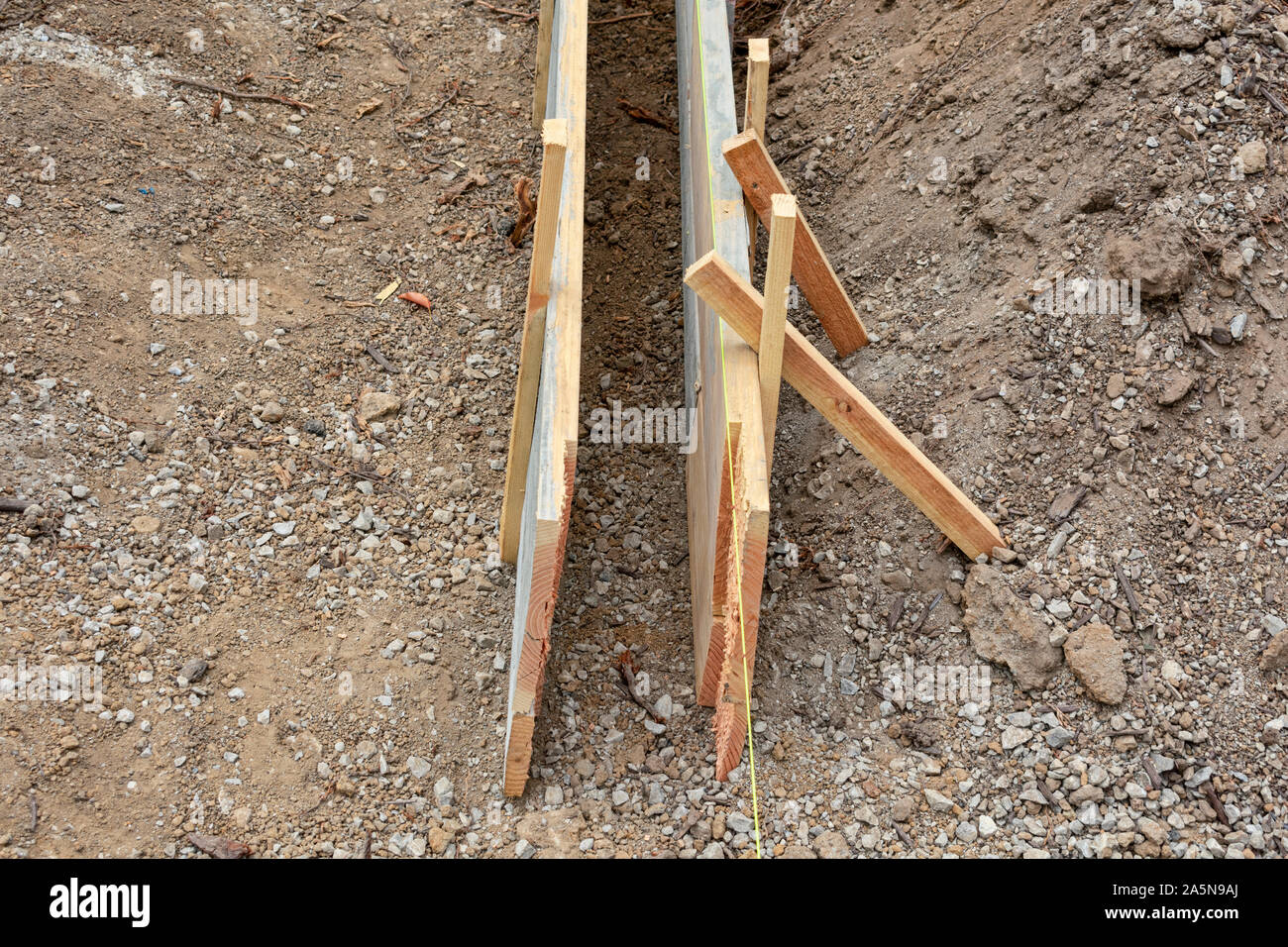 Concrete curb construction. Excavated area. Wood board secured upright ...