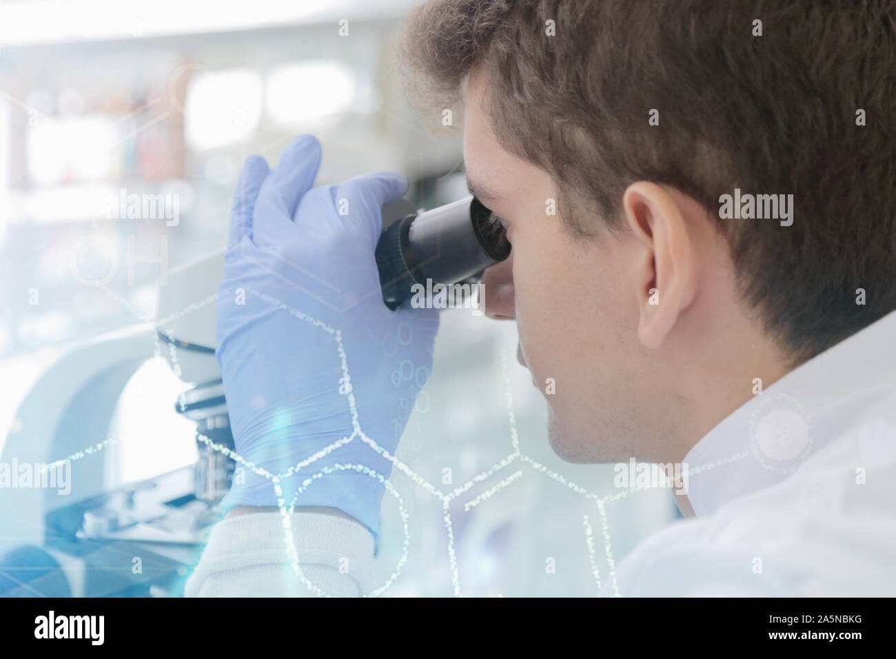 Youngmale male scientist looking through a microscope in a laboratory ...