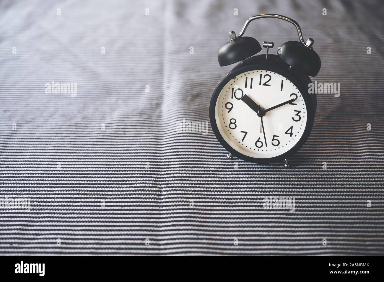 Closeup image of a black alarm clock on the table with blur background ...