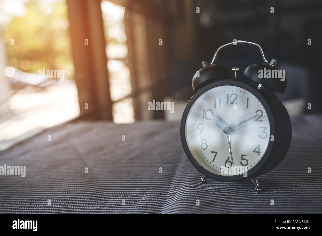 Closeup image of a black alarm clock on the table with blur background ...