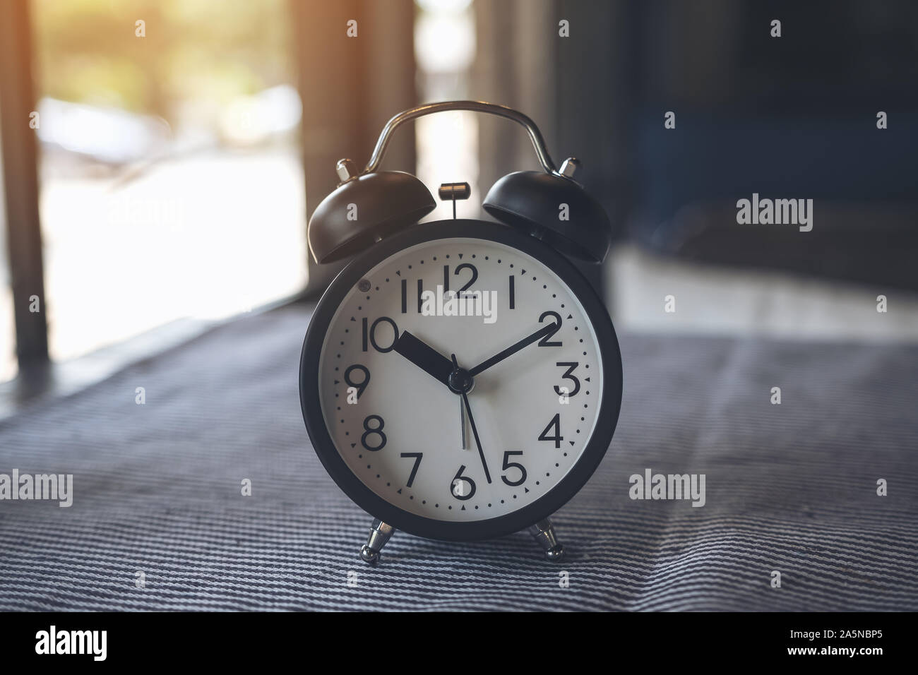 Closeup image of a black alarm clock on the table with blur background ...