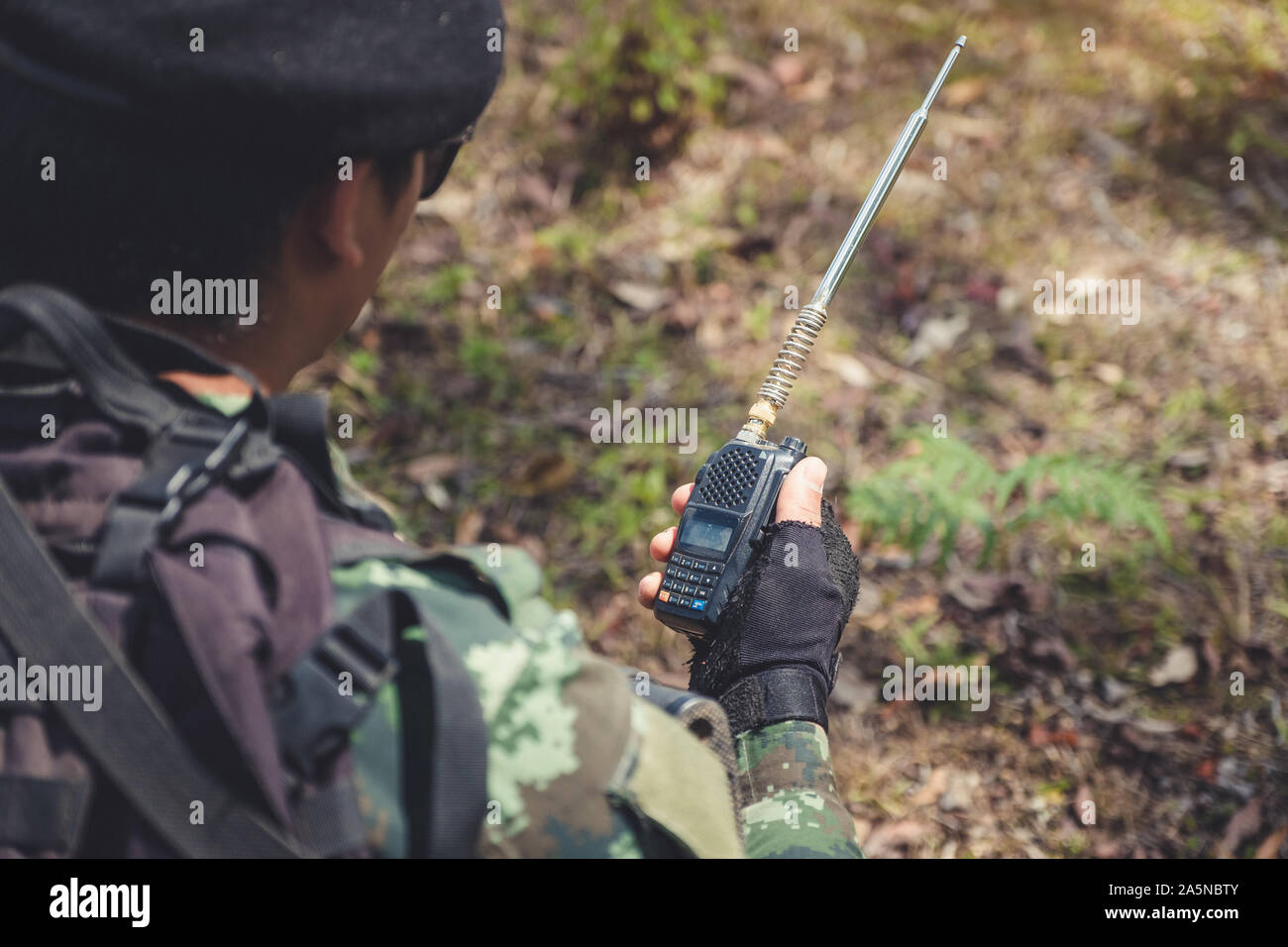 Closeup image of an armed soldier holding and using radio communication ...