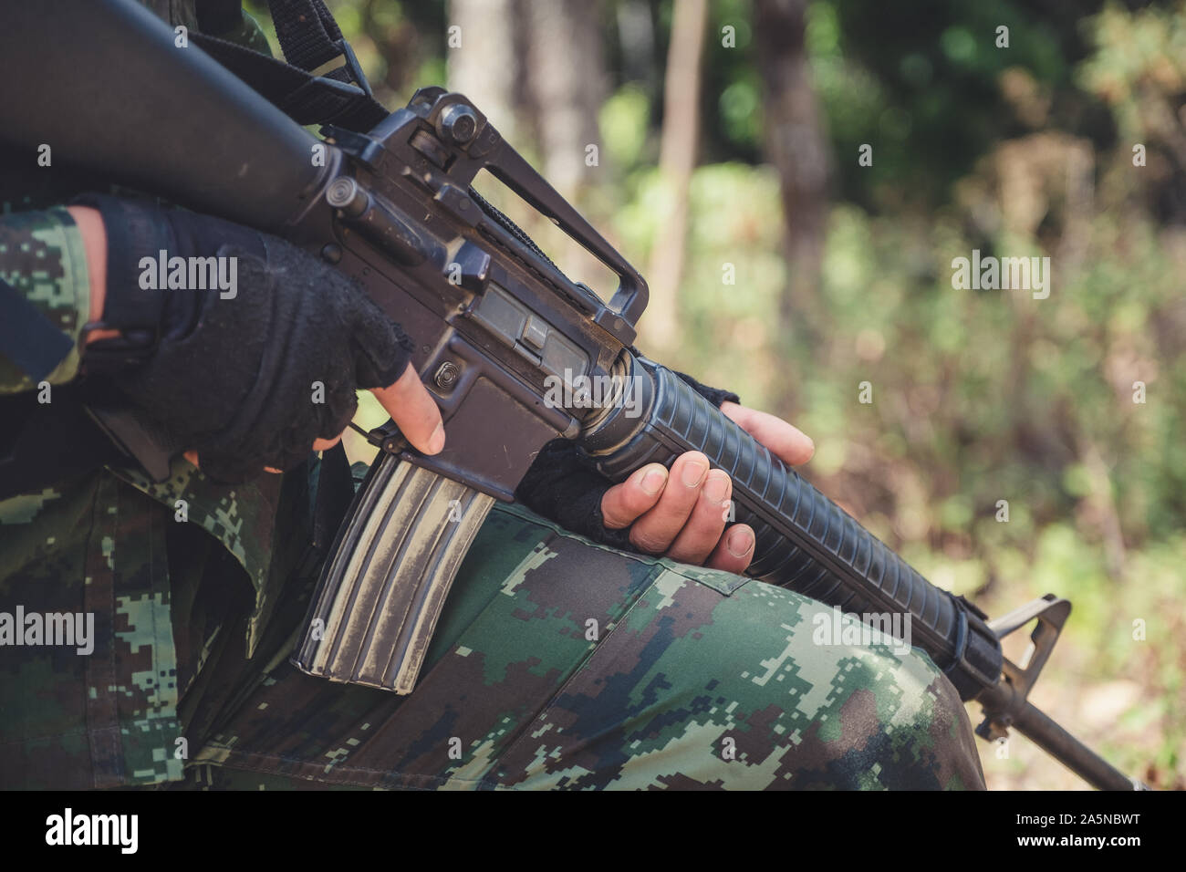 Closeup image of an armed soldier holding his gun in the battle field ...