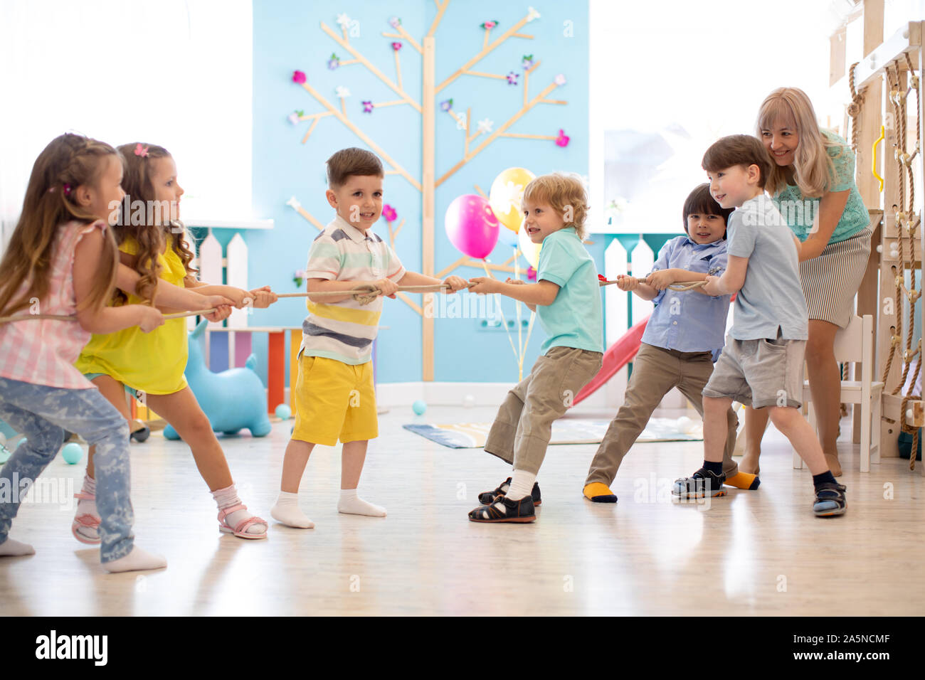 Group of children in a rope-pulling contest indoors Stock Photo - Alamy