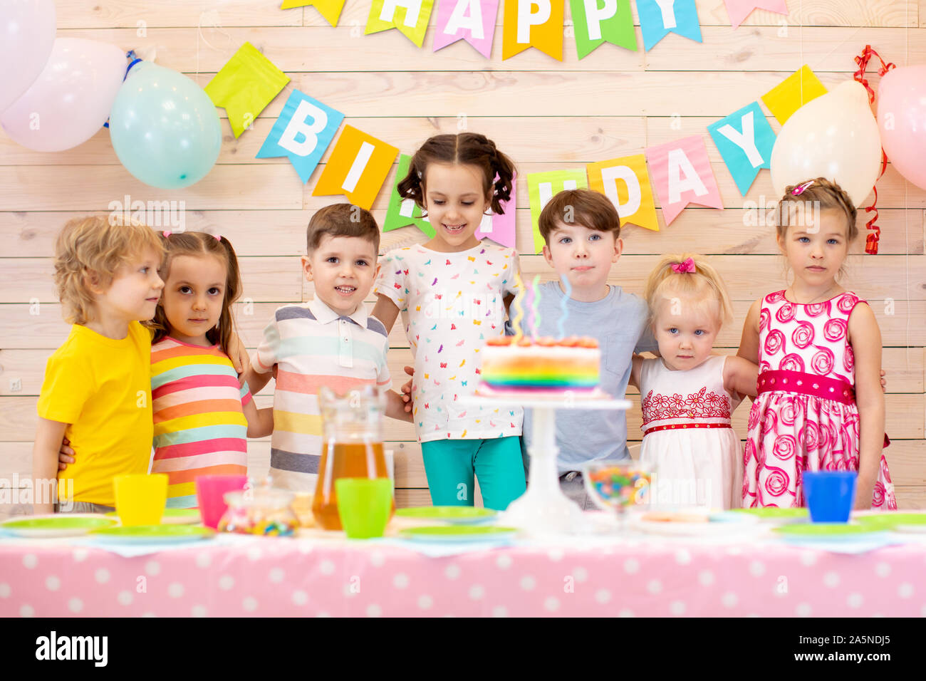 Group of adorable kids standing around festive table at birthday party ...