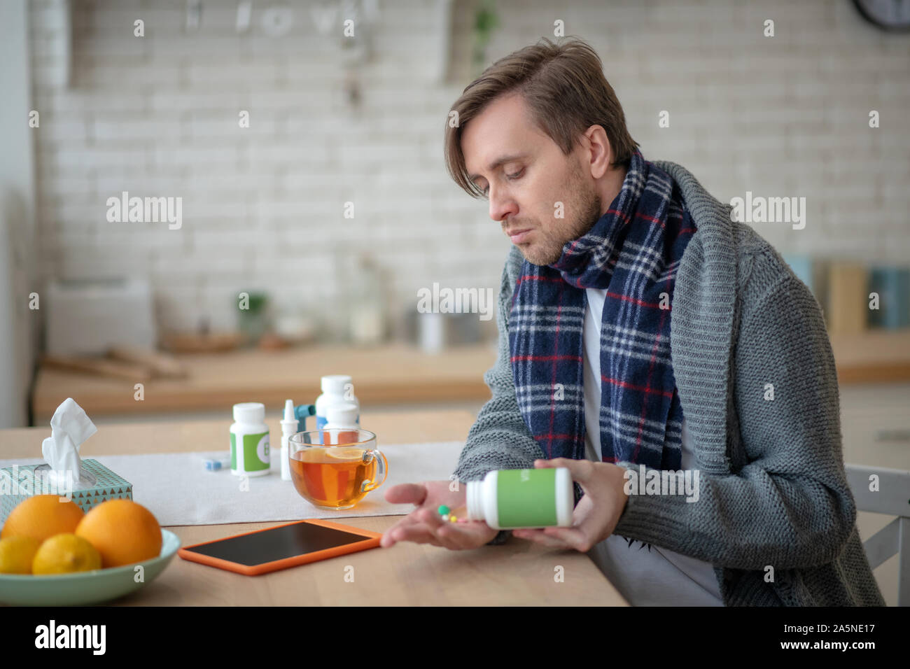 Sick man taking medication after drinking hot tea Stock Photo - Alamy