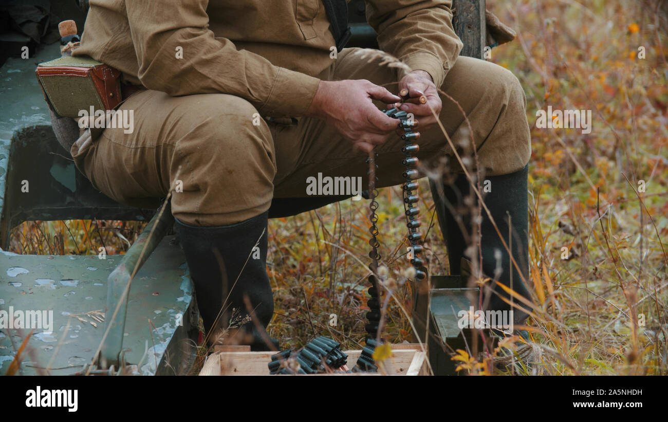 A soldier prepares the ammunition for charging in the machine gun ...