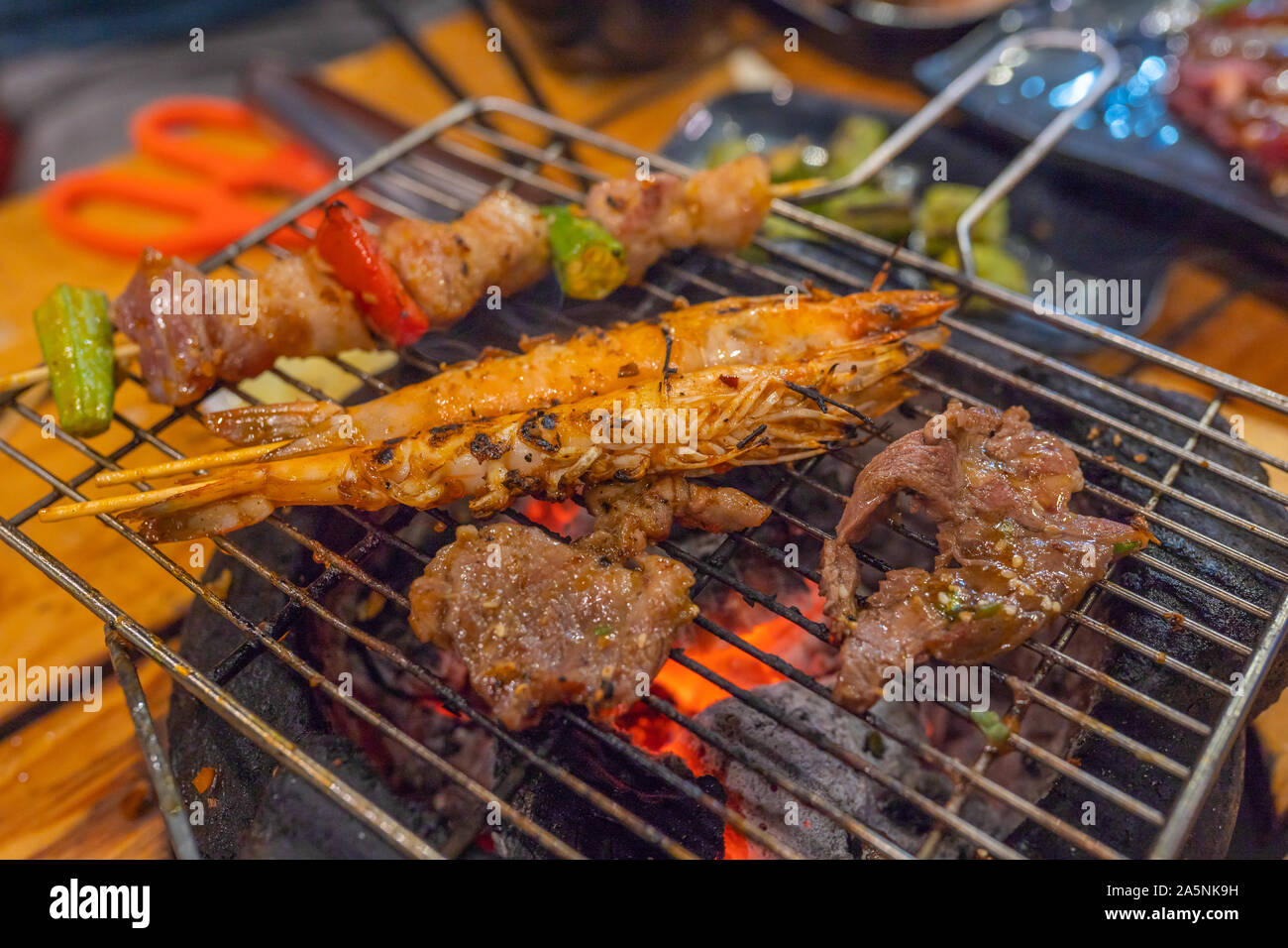 Meat slices, pork kebab and shrimp on flaming charcoal stove Stock ...