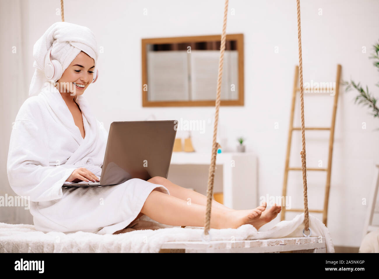 woman in bathrobe and towel after shower uses laptop in bedroom Stock ...