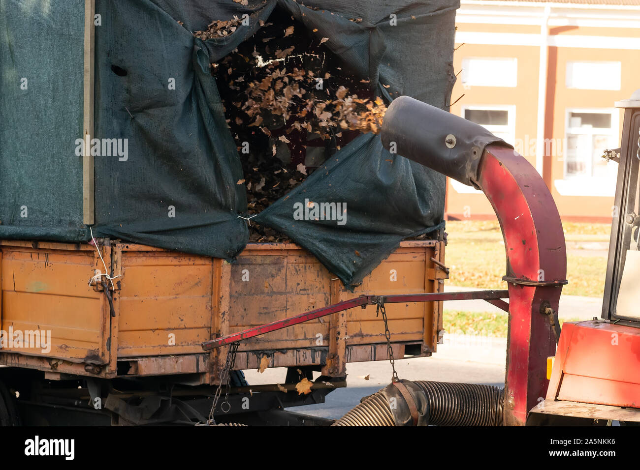 Heavy industrial vaccuum loader loading fallen leaves and junk into ...