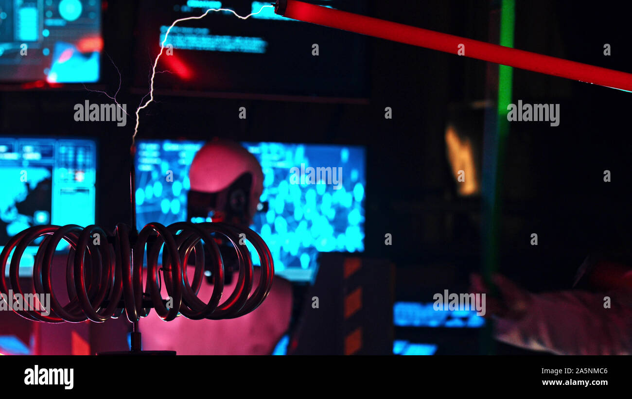 A man is touching a current by glowing lamps in a room with screens ...