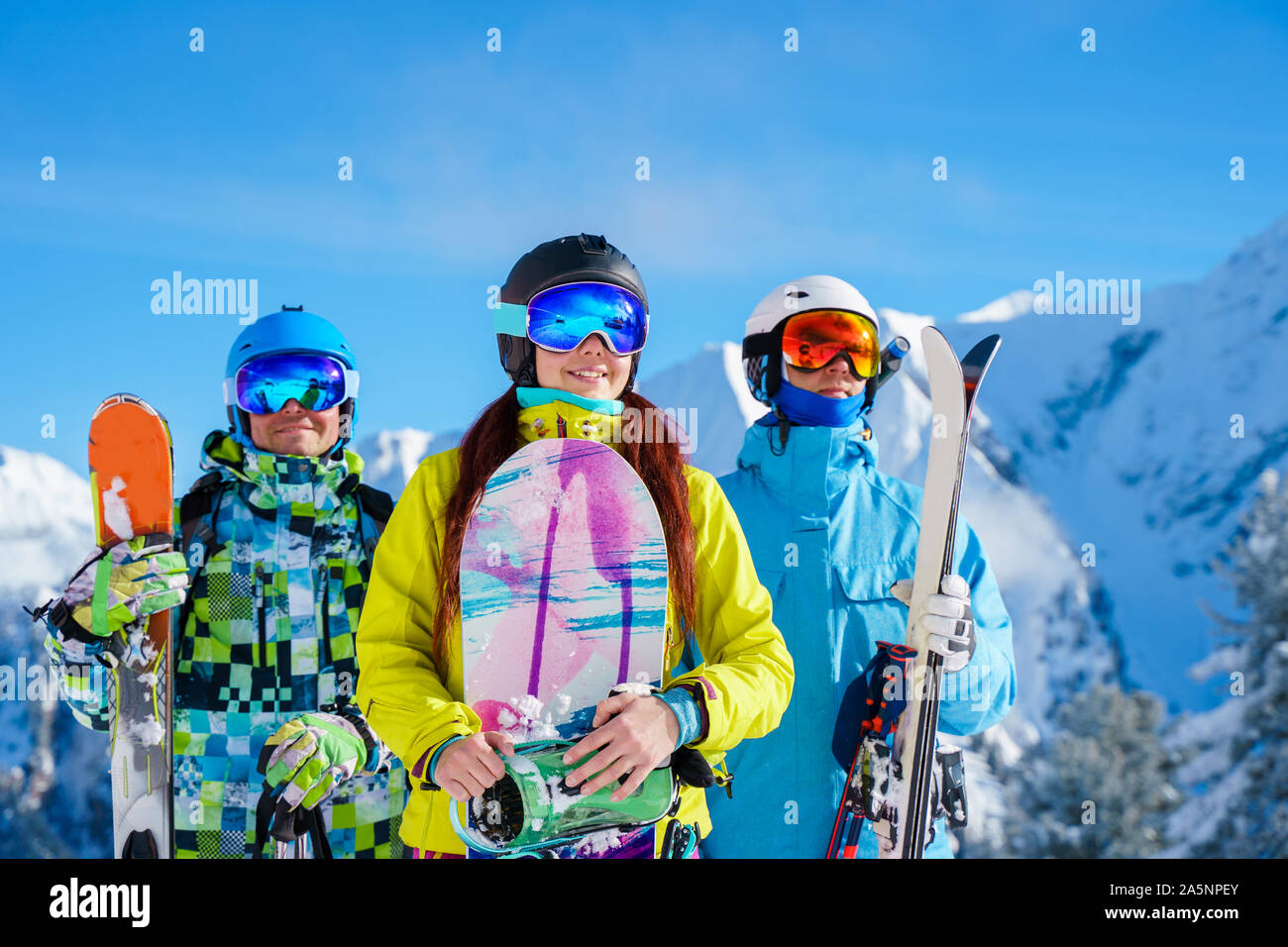 Happy man and woman with snowboard and skis standing on snow resort ...