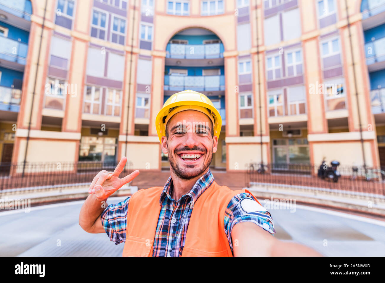 Happy man architect at a building site takes a selfie looking at the ...
