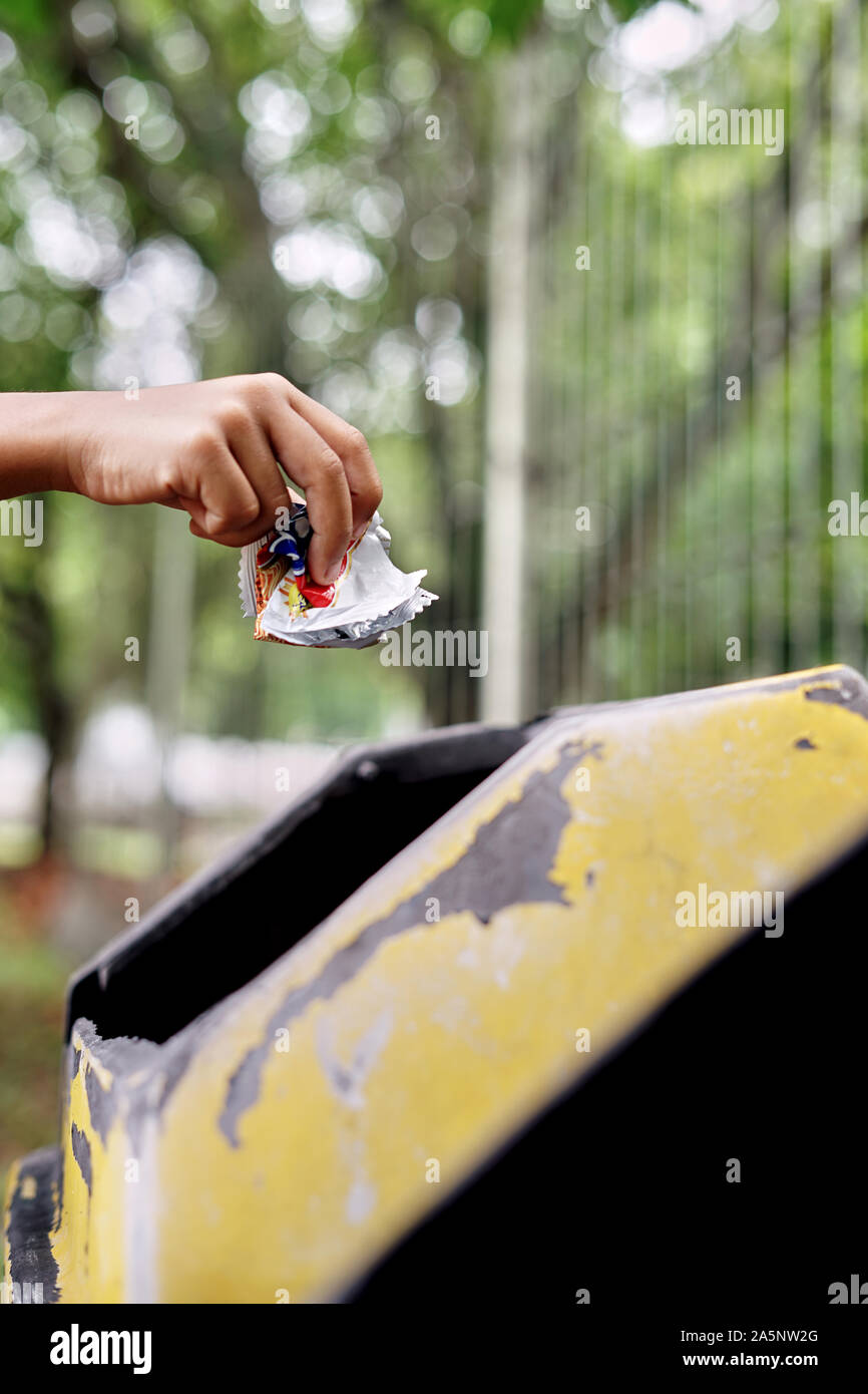 Close up children hand throwing plastic trash into the recycling trash ...