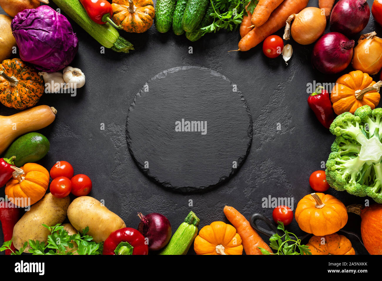 Culinary background with fresh raw vegetables on a black kitchen table ...