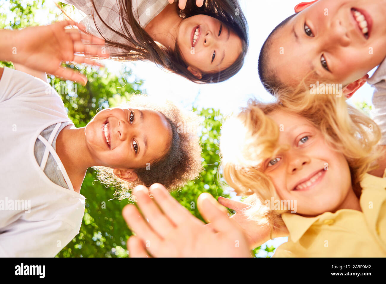 Cheerful children in a multicultural kindergarten wave at the camera ...