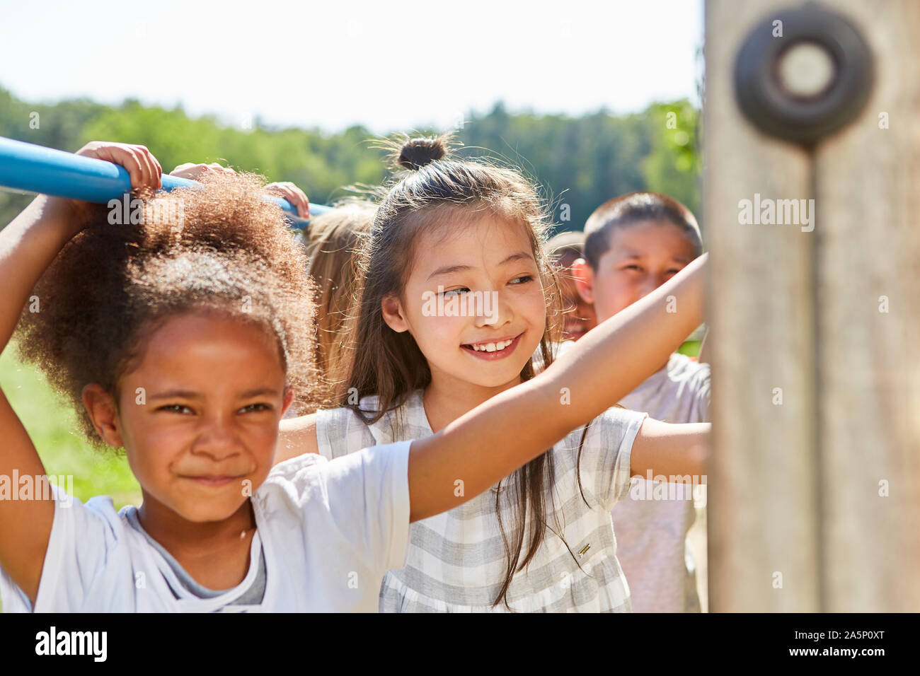 Girl and multicultural friends do gymnastics on climbing frame on ...