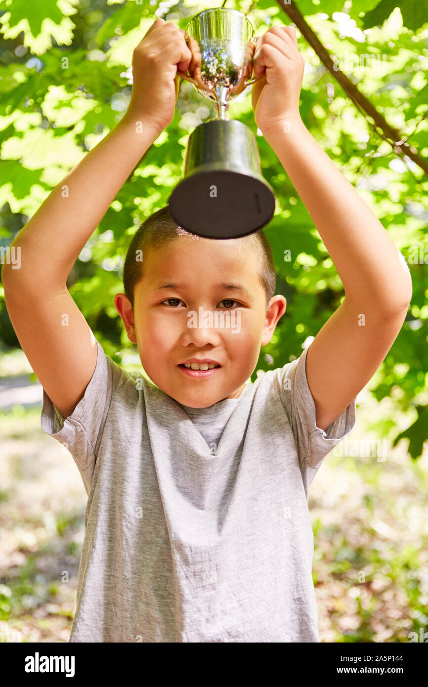 Asian boy is happy about a win and holds the trophy high Stock Photo ...