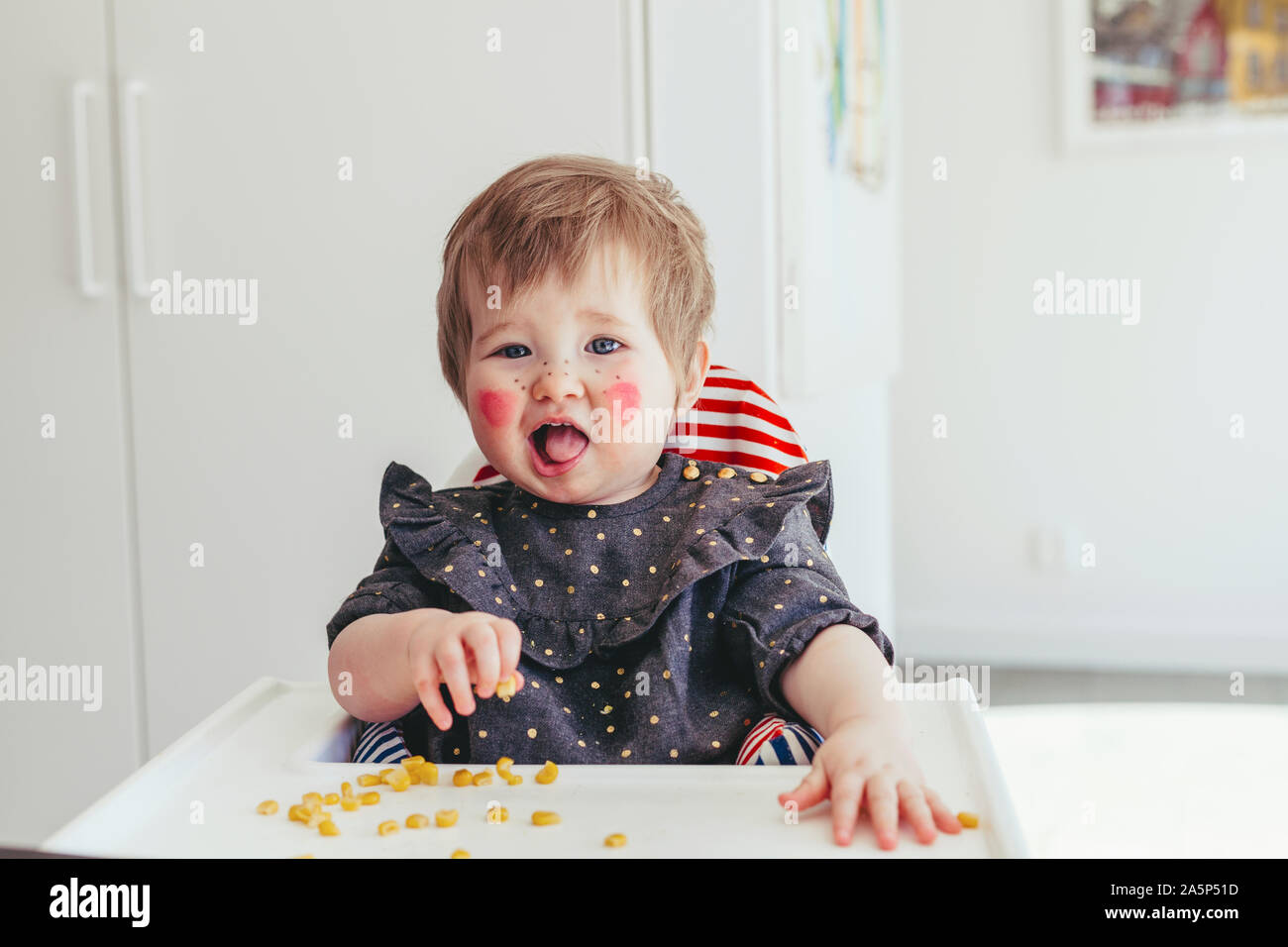 Girl sitting in high chair Stock Photo - Alamy